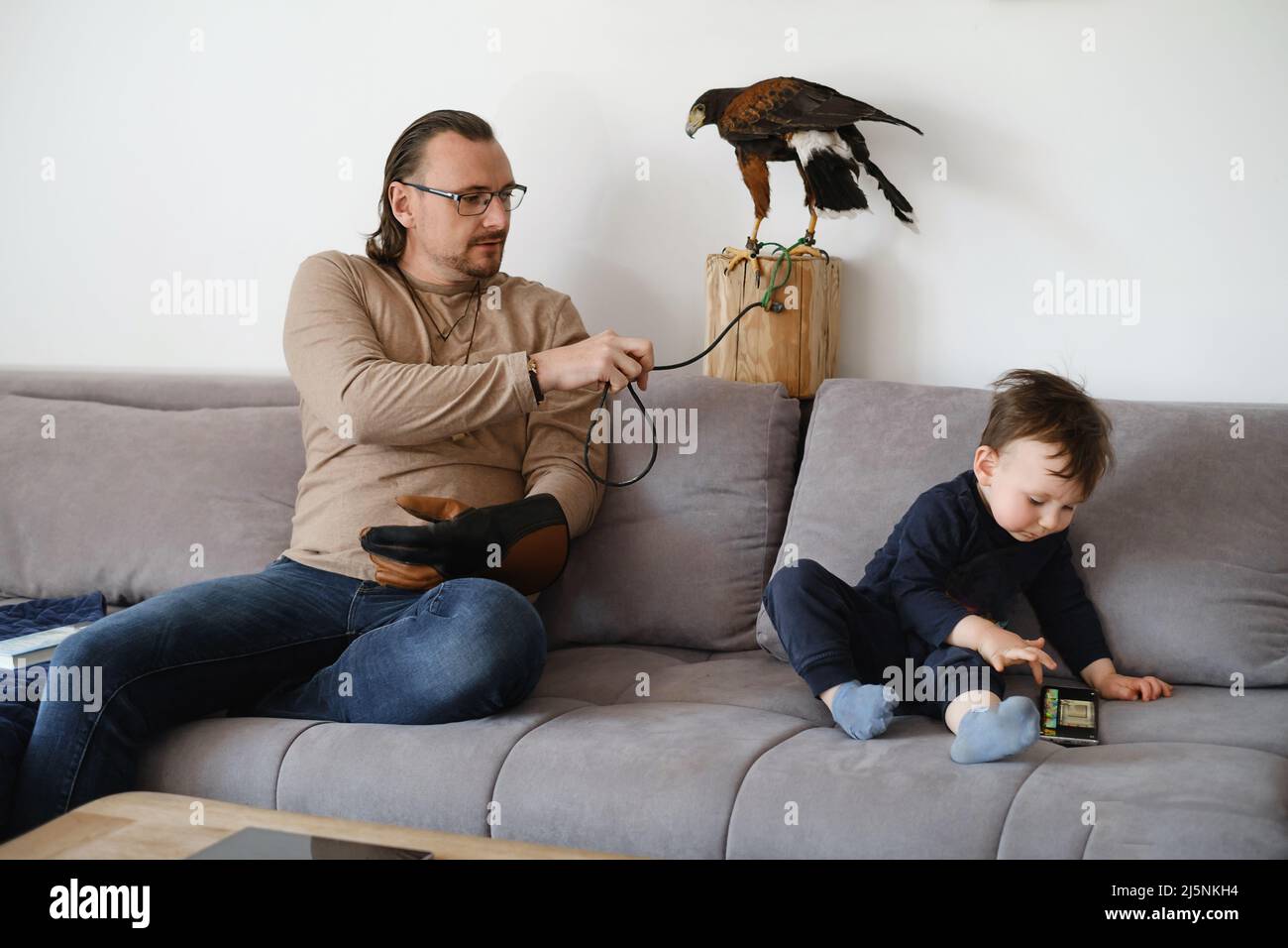 Father with child and wild bird buzzard sitting on the coach, reading ...