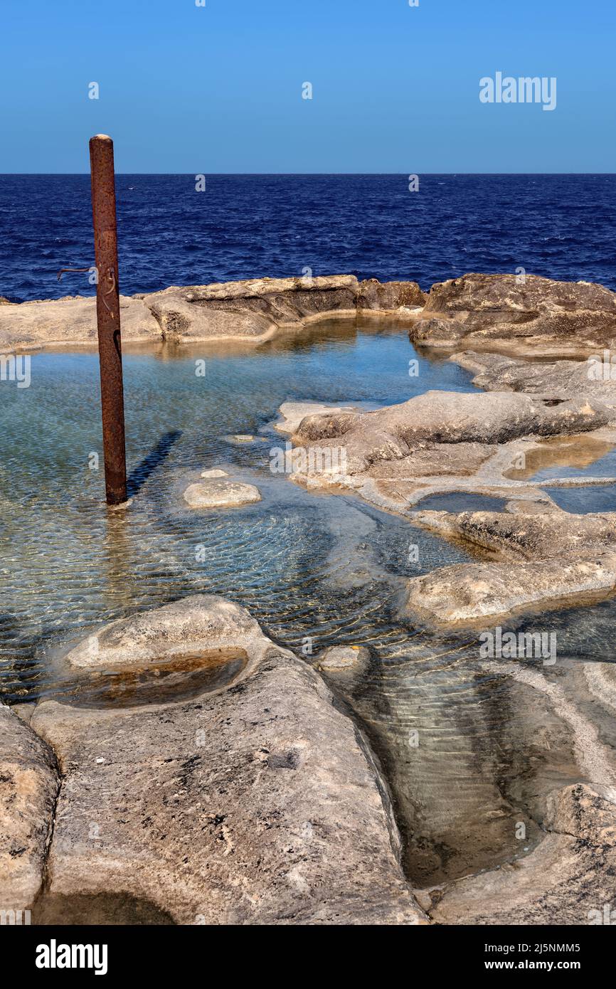 Malta island old sea waterfront with shallow water and rusty metal pole ...