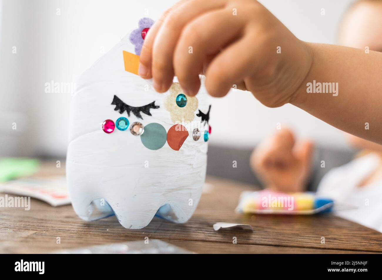 Caucasian preschool girl doing crafts with plastic bottle and paints ...