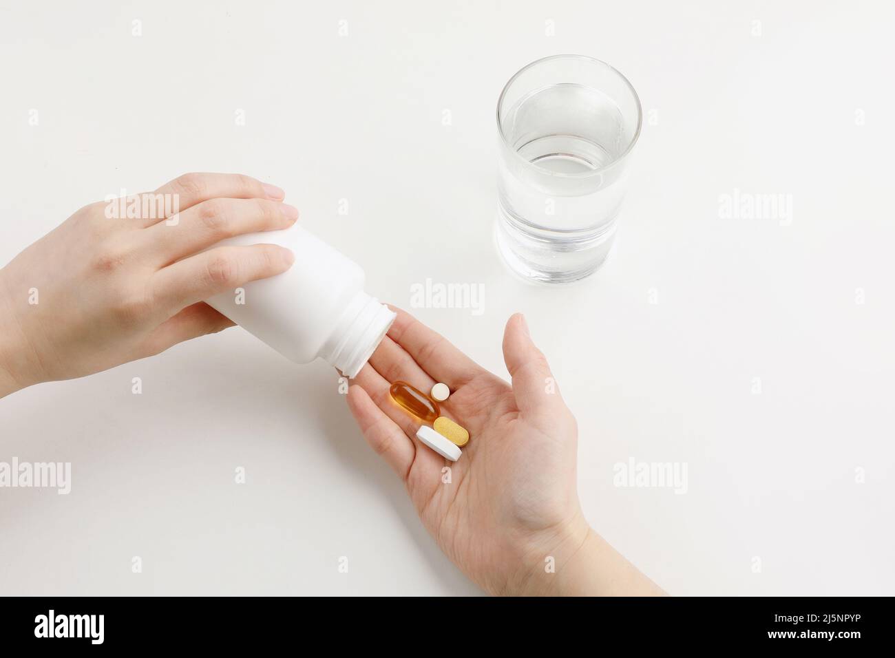 a cup of water and hand motion to take out pills, white background ...