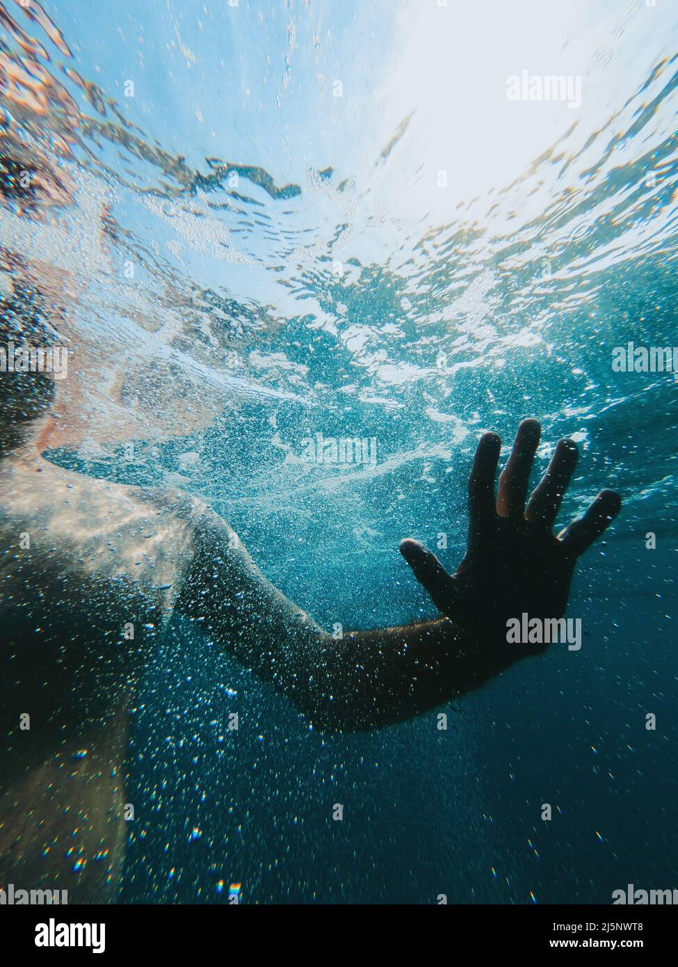 Underwater shot of male person swimming in sea water with bubbles and ...