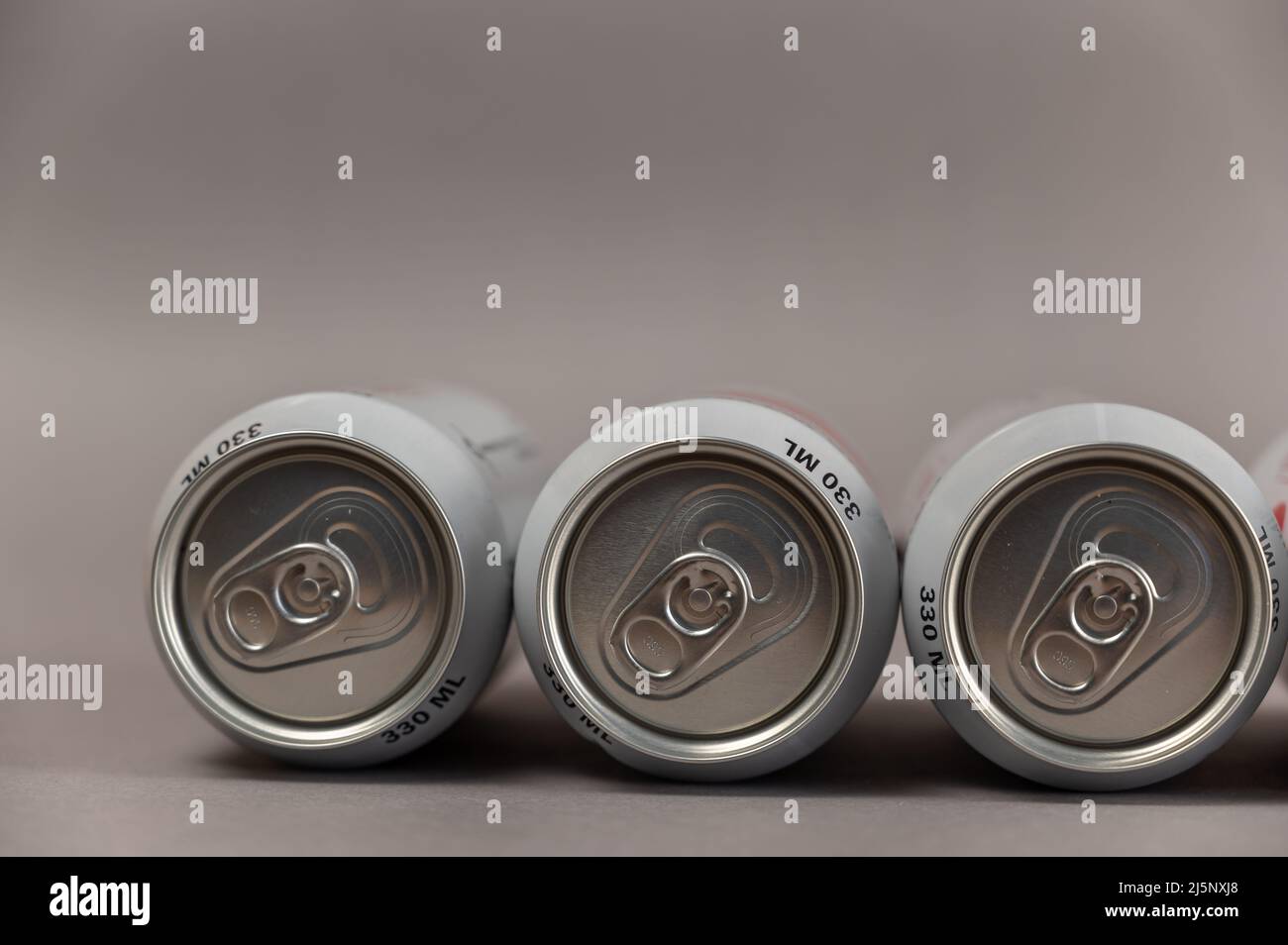 Three full tin cans lie against the gray background. Cylindrical silver ...