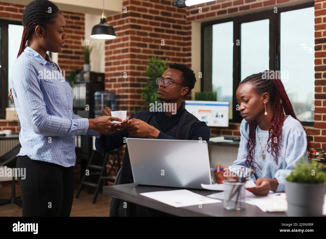 African american assistant offering to project manager a cup of coffee ...