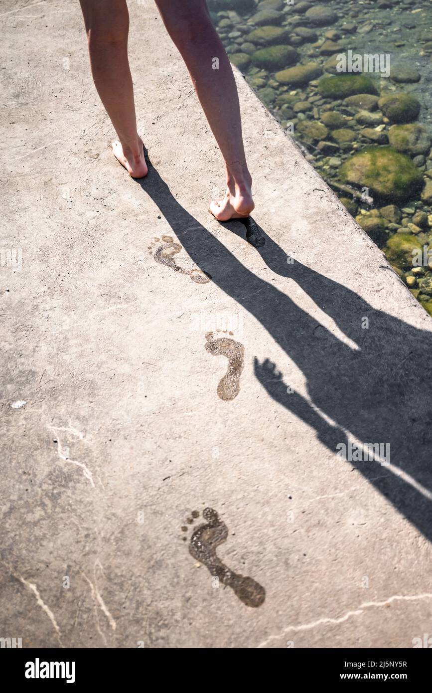 Woman walks and leaves wet footprint Stock Photo - Alamy