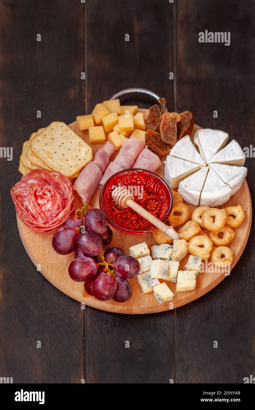 Appetizers board with assorted cheese, meat, sausage rosette, grape and ...