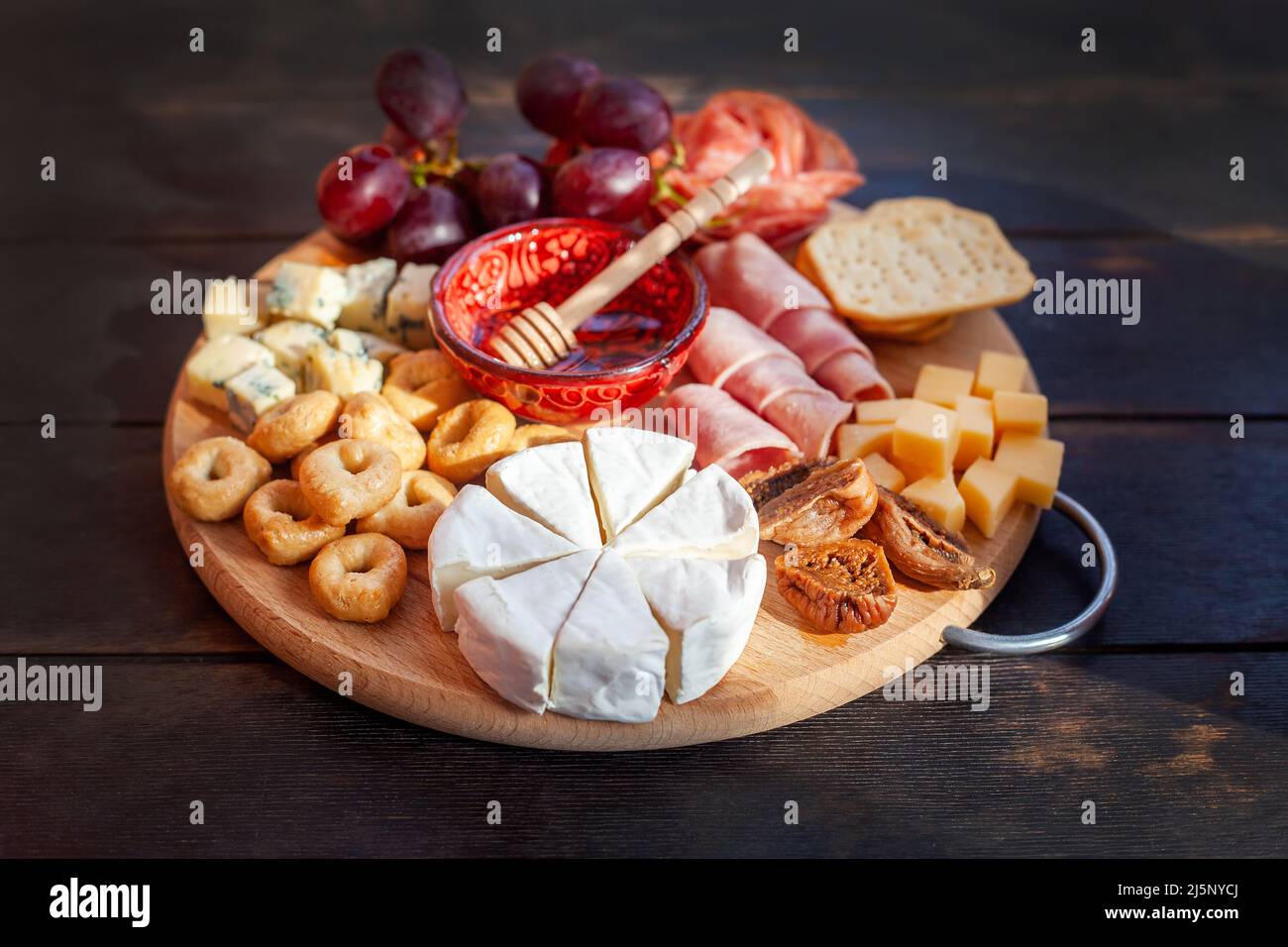 Round cutting board with slicing assorted cheese, sausage rosette, ham ...
