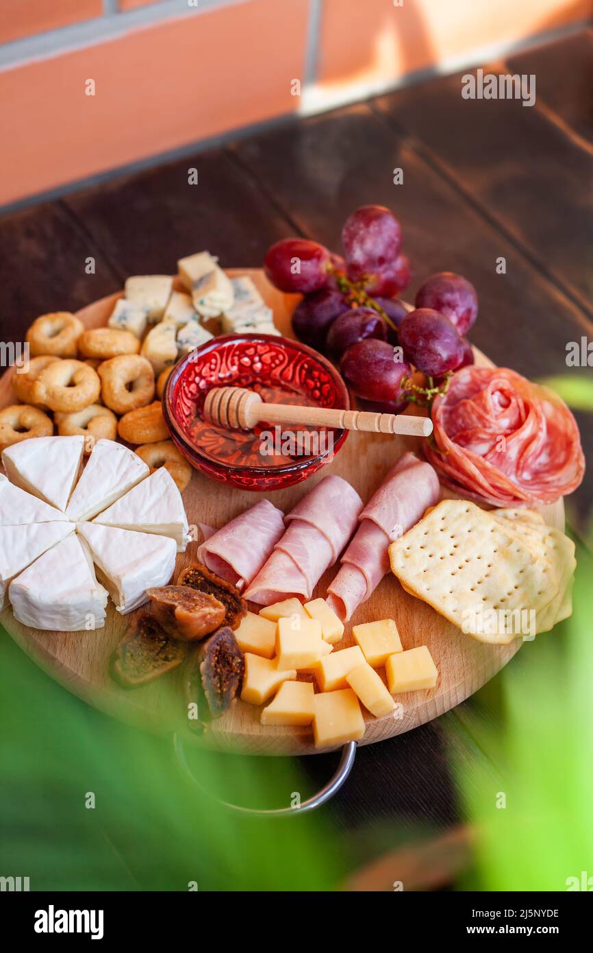 Round cutting board with slicing assorted cheese, sausage rosette, ham ...