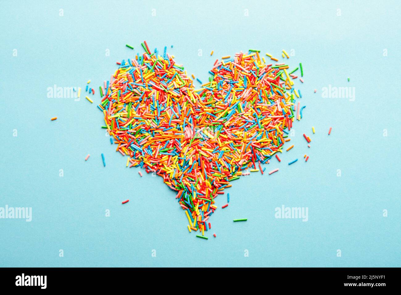 Simple concept flatlay with a heart made of colorful sugar sprinkles ...