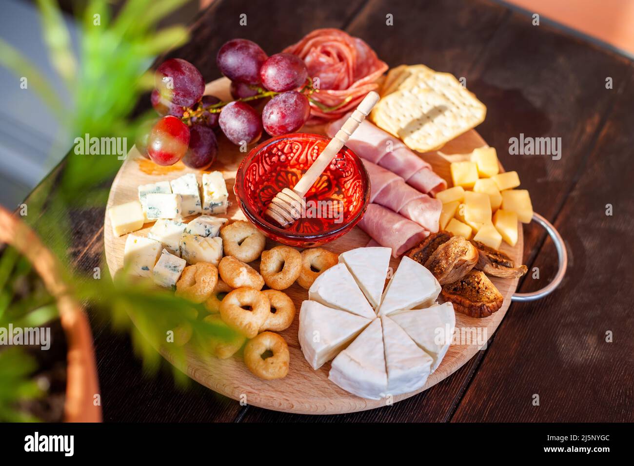 Round cutting board with slicing assorted cheese, sausage rosette, ham ...