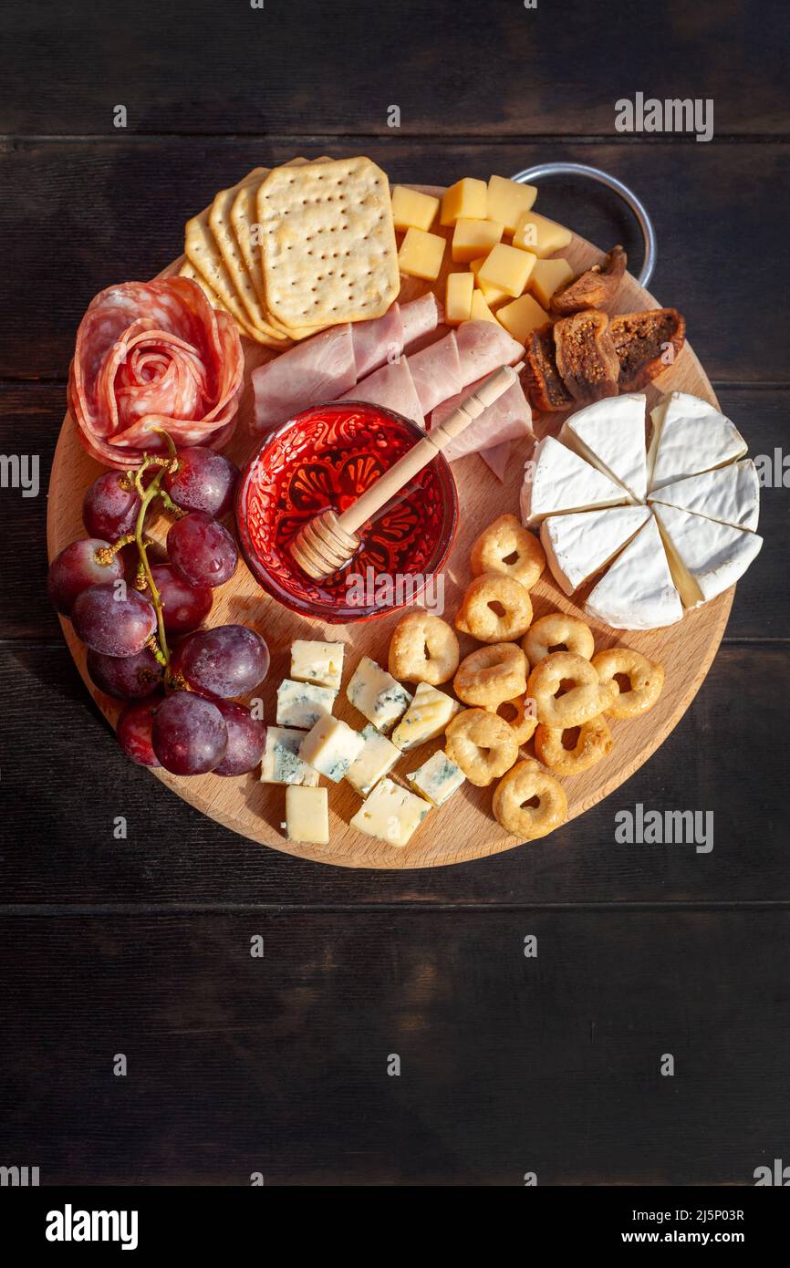 Appetizers board with assorted cheese, meat, sausage rosette, grape and ...