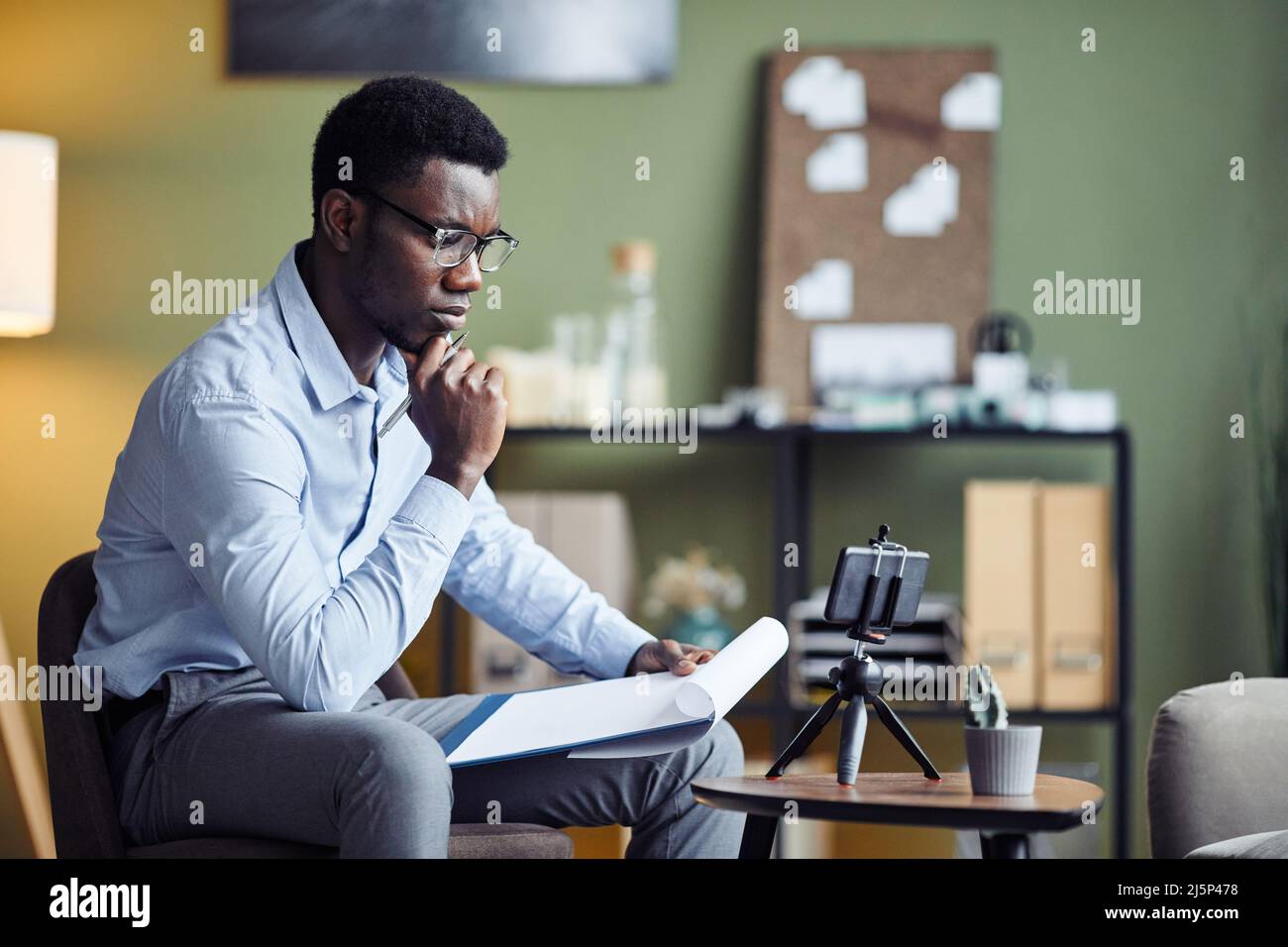 Concentrated psychologist reading notes before recording video for ...