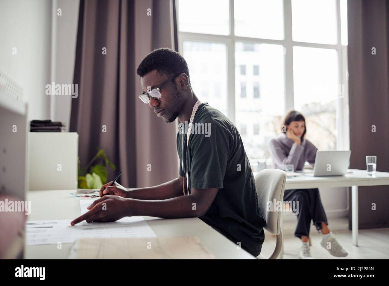 Focused young Black fashion designer drawing sketch of new clothes ...