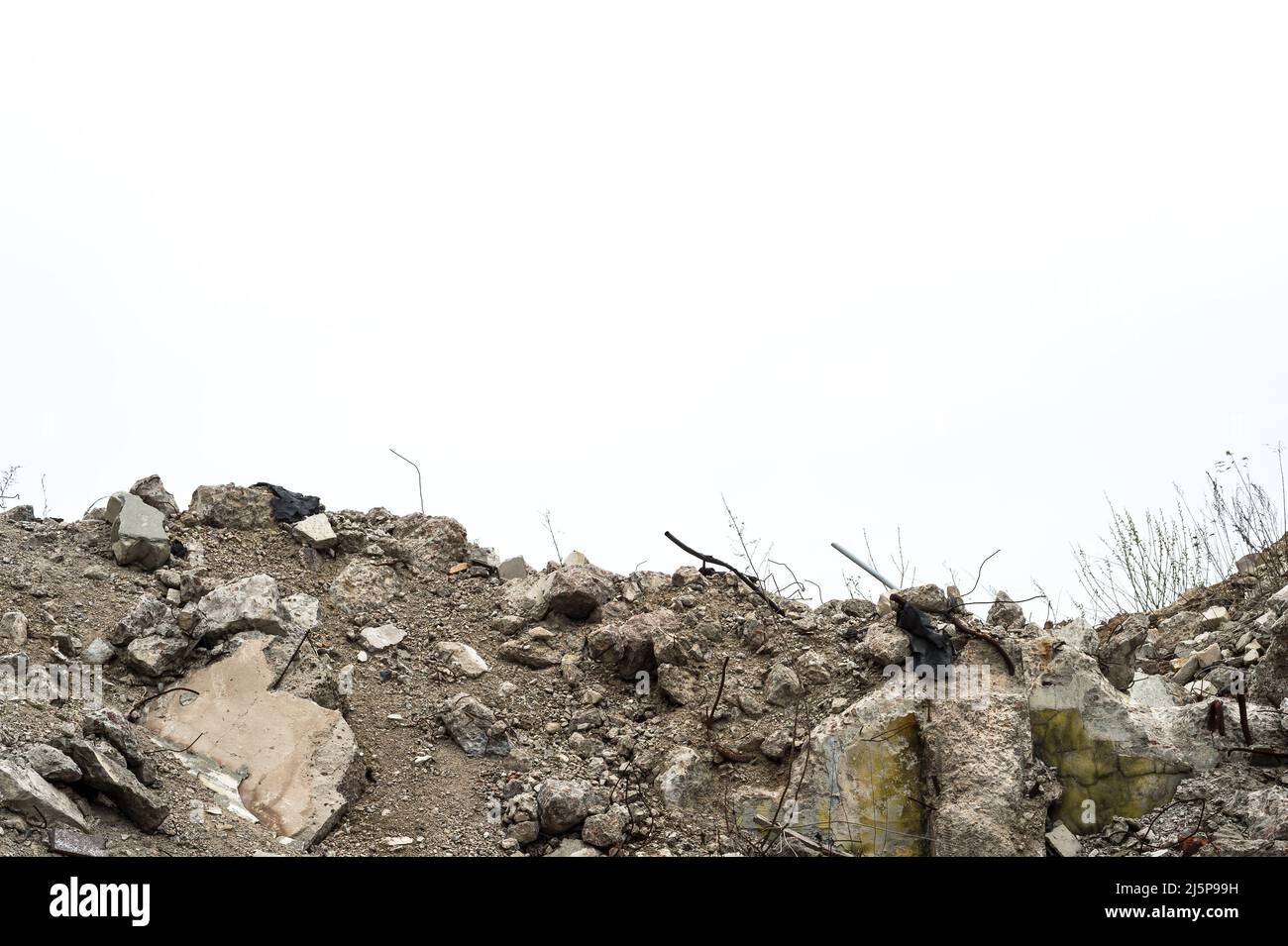 A mound of concrete rubble and construction debris against a gray sky ...