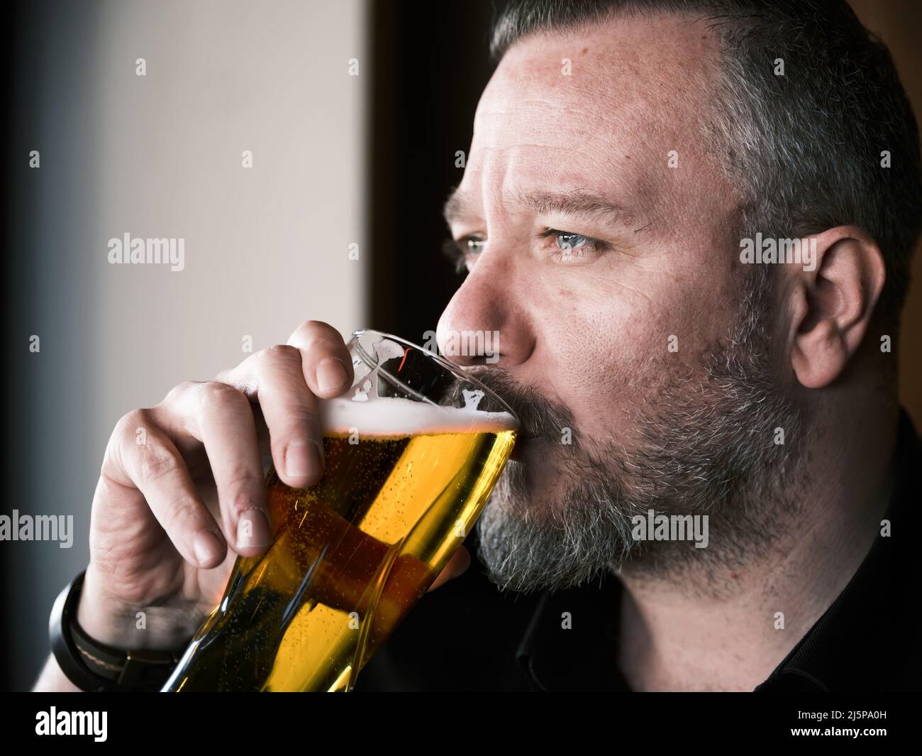 Close up portrait of a hipster man in his 40s drinking a glass of beer ...
