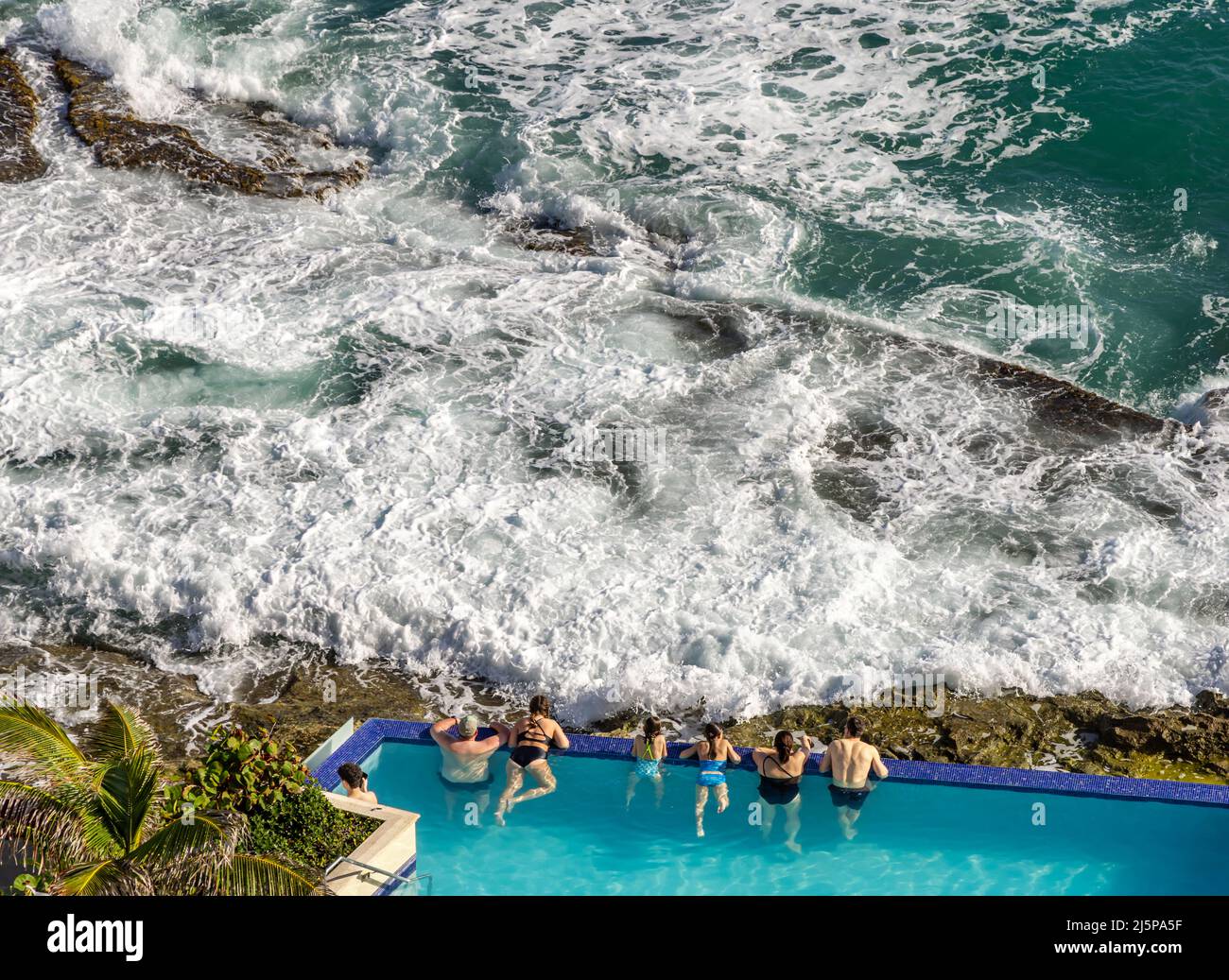 people in an infinity pool watching the ocean at The Condado Vanderbilt ...