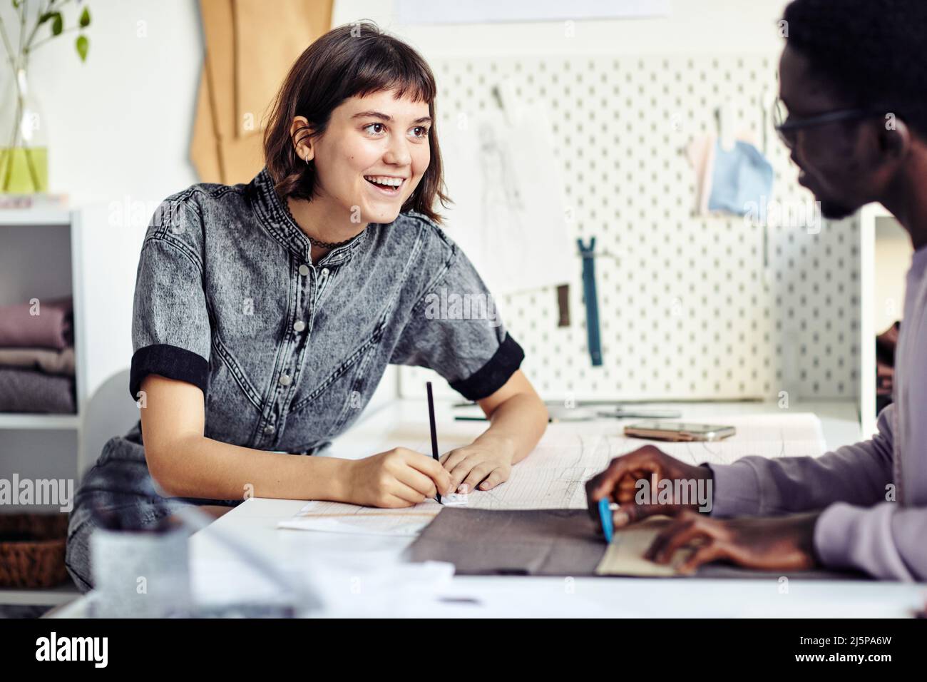 Excited young female fashion designer drawing sewing pattern and ...