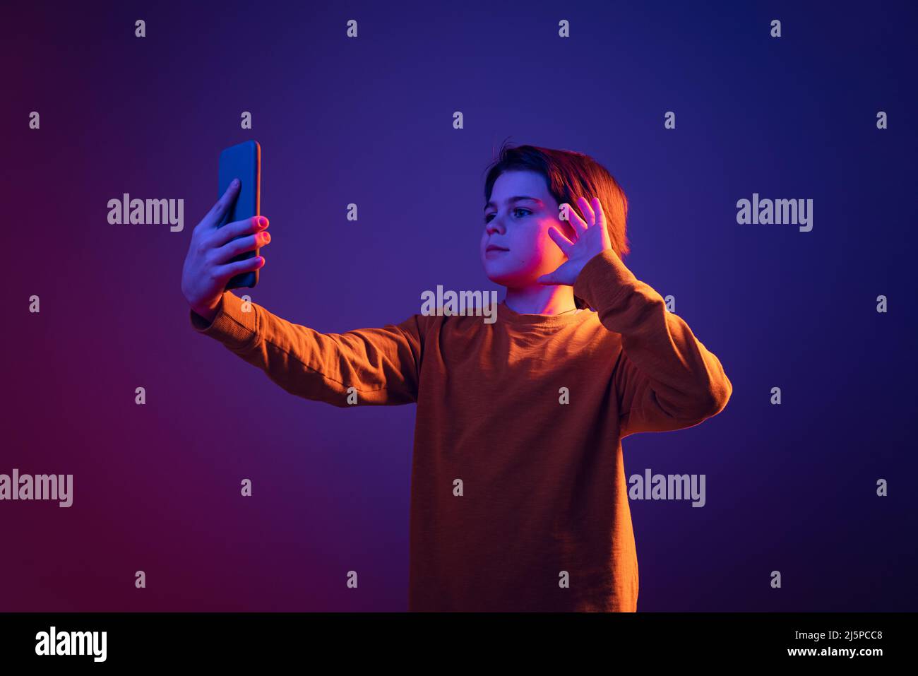 Portrait of boy, child having online video call on phone, waving hand ...