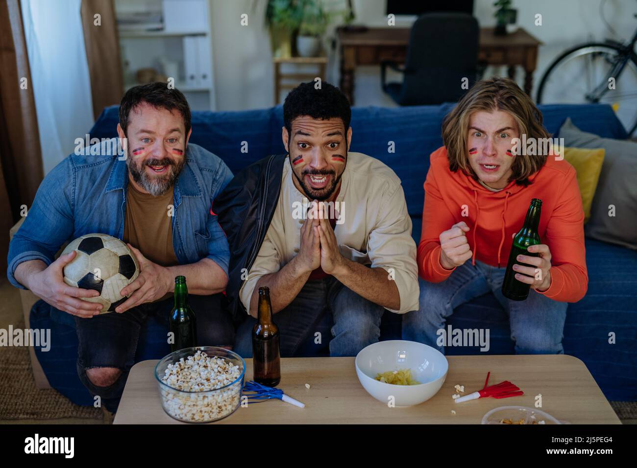 Nervous football fans friends staring at TV and watching football match ...