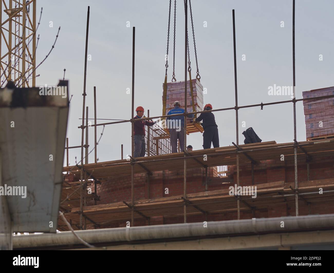 Workers at the construction site take a load of bricks Stock Photo - Alamy