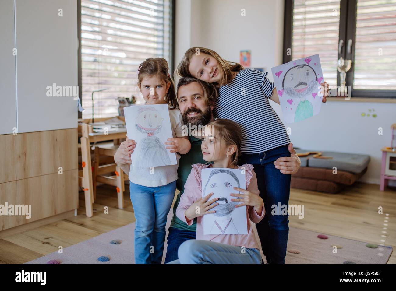 Father of three little daughters getting drawings from them at home ...