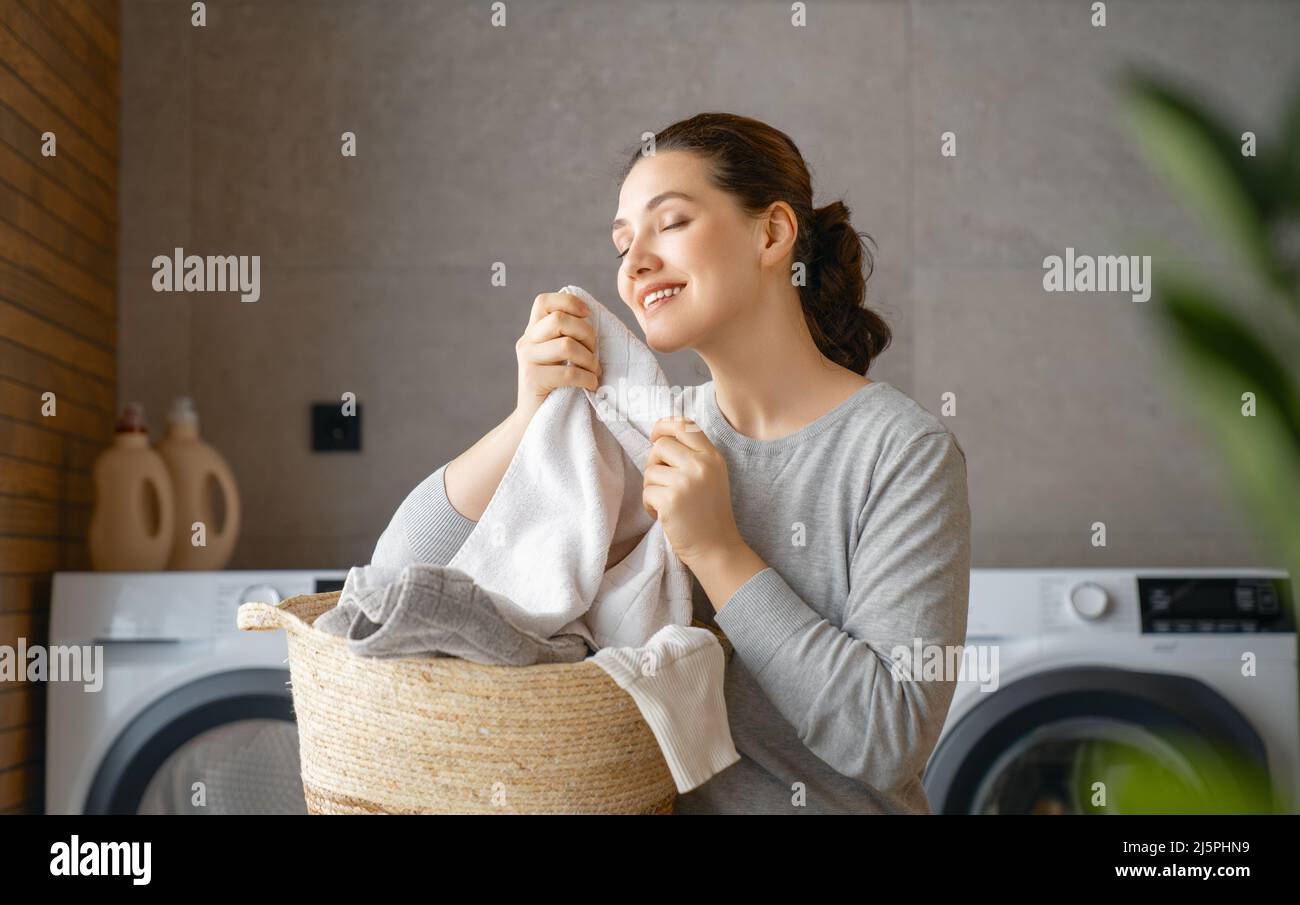 Beautiful young woman is smiling while doing laundry at home Stock Photo - Alamy