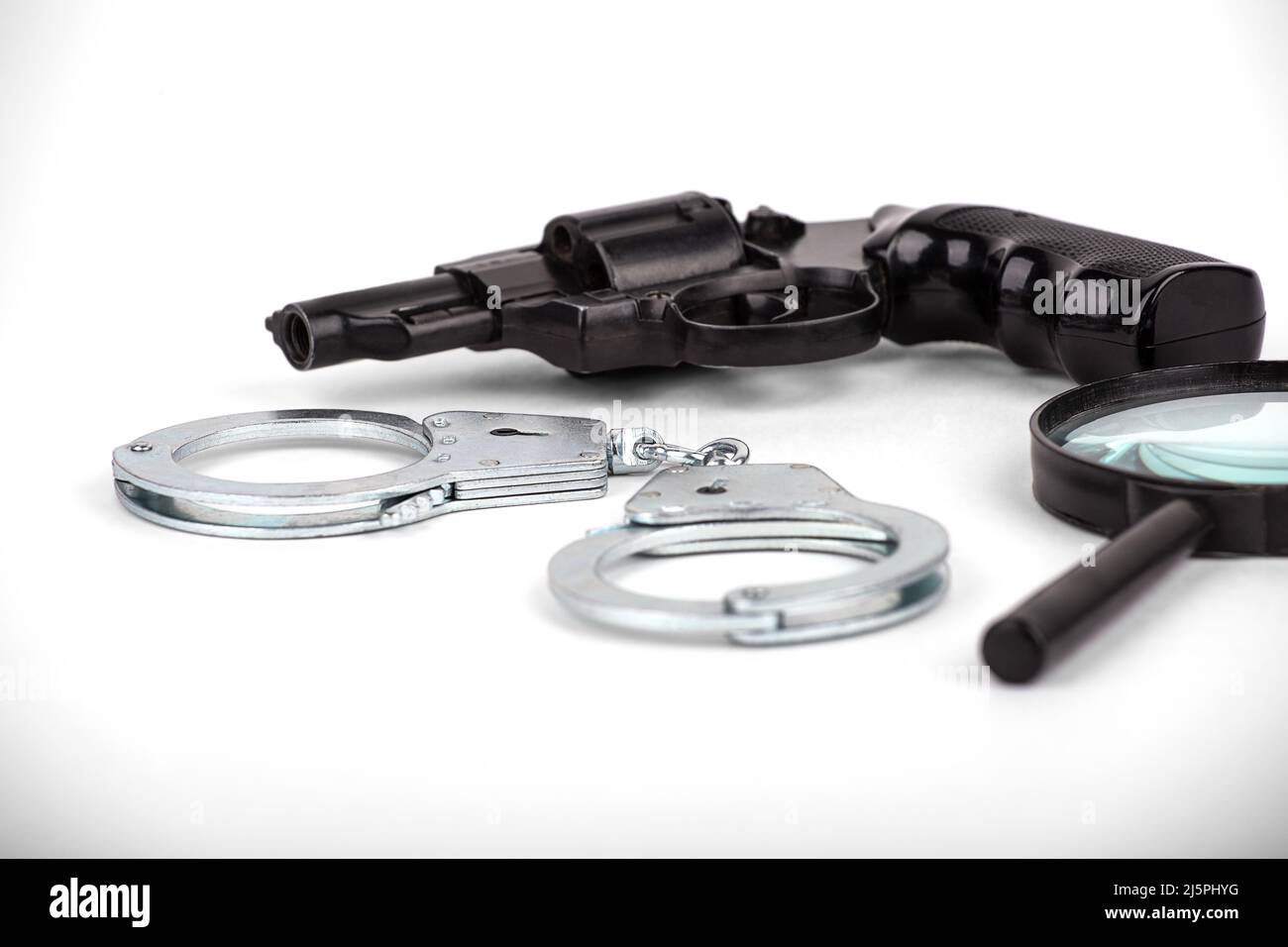 Handcuffs, pistol and magnifying glass, isolated on a white background ...