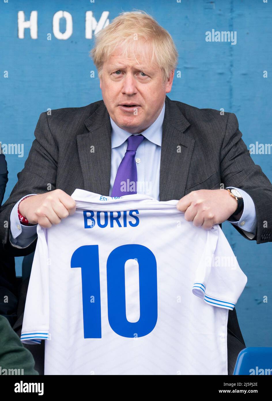 Prime Minister Boris Johnson holds a shirt with his name as he sits ...