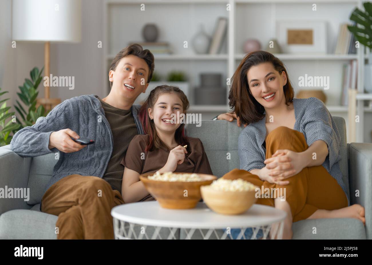 Happy family watching projector, TV, movies with popcorn in the evening ...