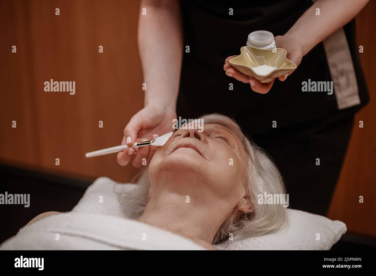 Cosmetologist applying facial revitalizing mask on a womans face Stock ...