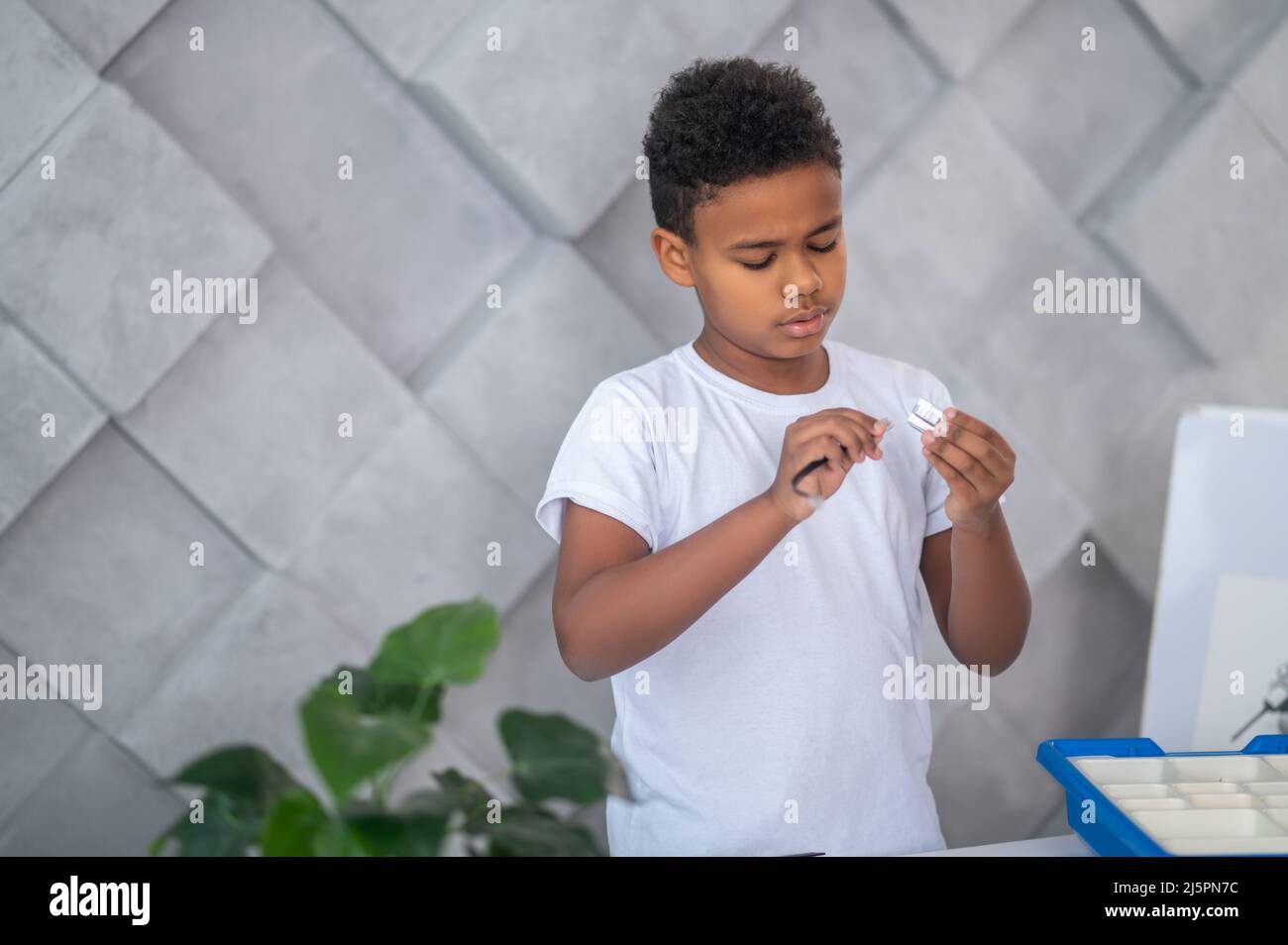 A cute teen looking busy while assembling some small pieces Stock Photo ...