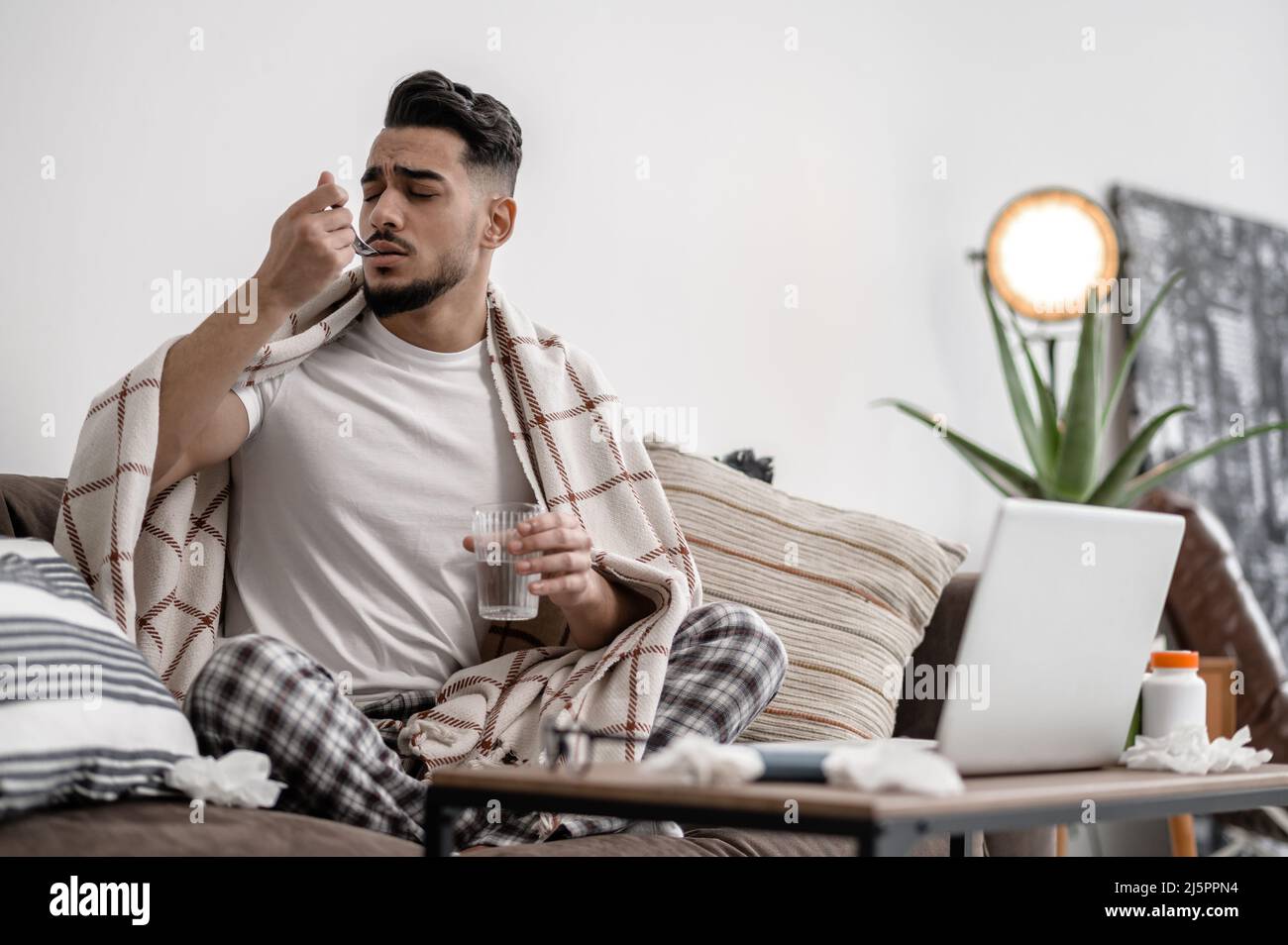 A sick man taking a spoon with medicine Stock Photo - Alamy