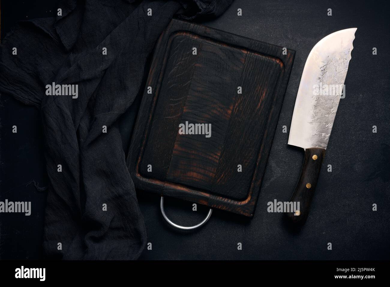 rectangular empty wooden cutting board and kitchen knife on black table ...