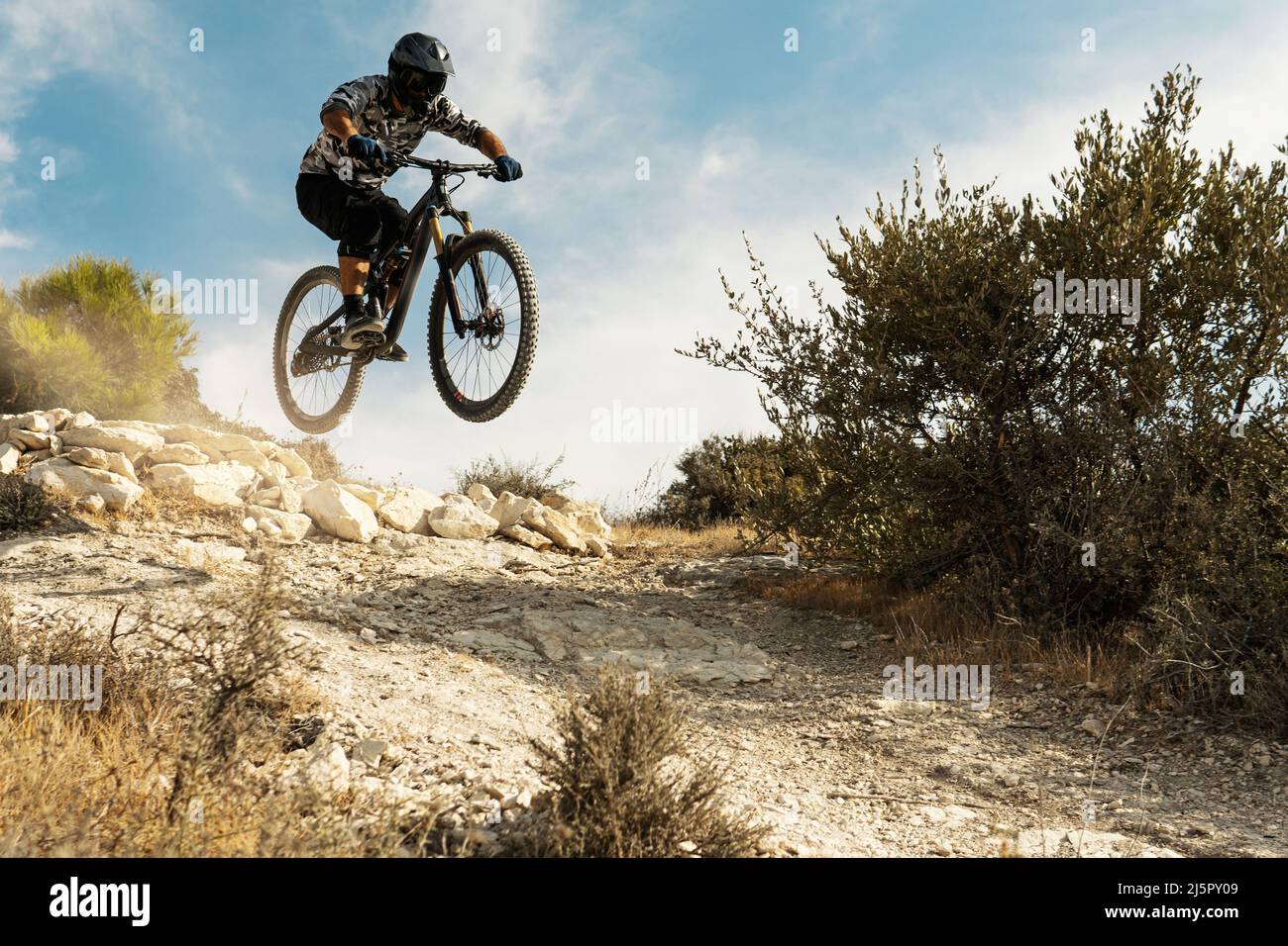Professional bike rider jumping during downhill ride on his bicycle in ...