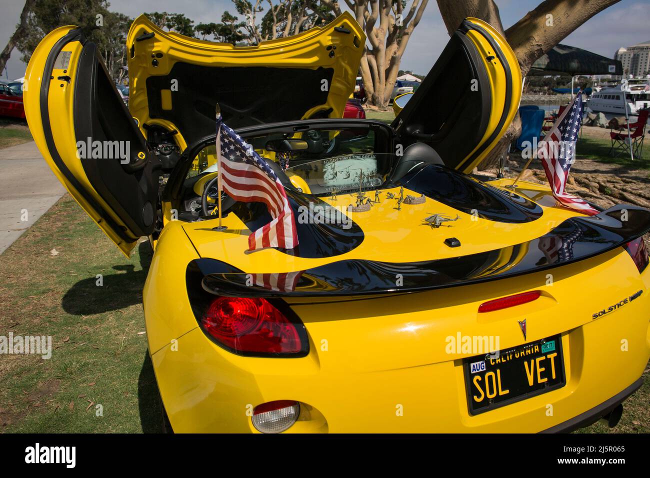 Yellow Solstice car, covered by war toys and American flags, in a ...