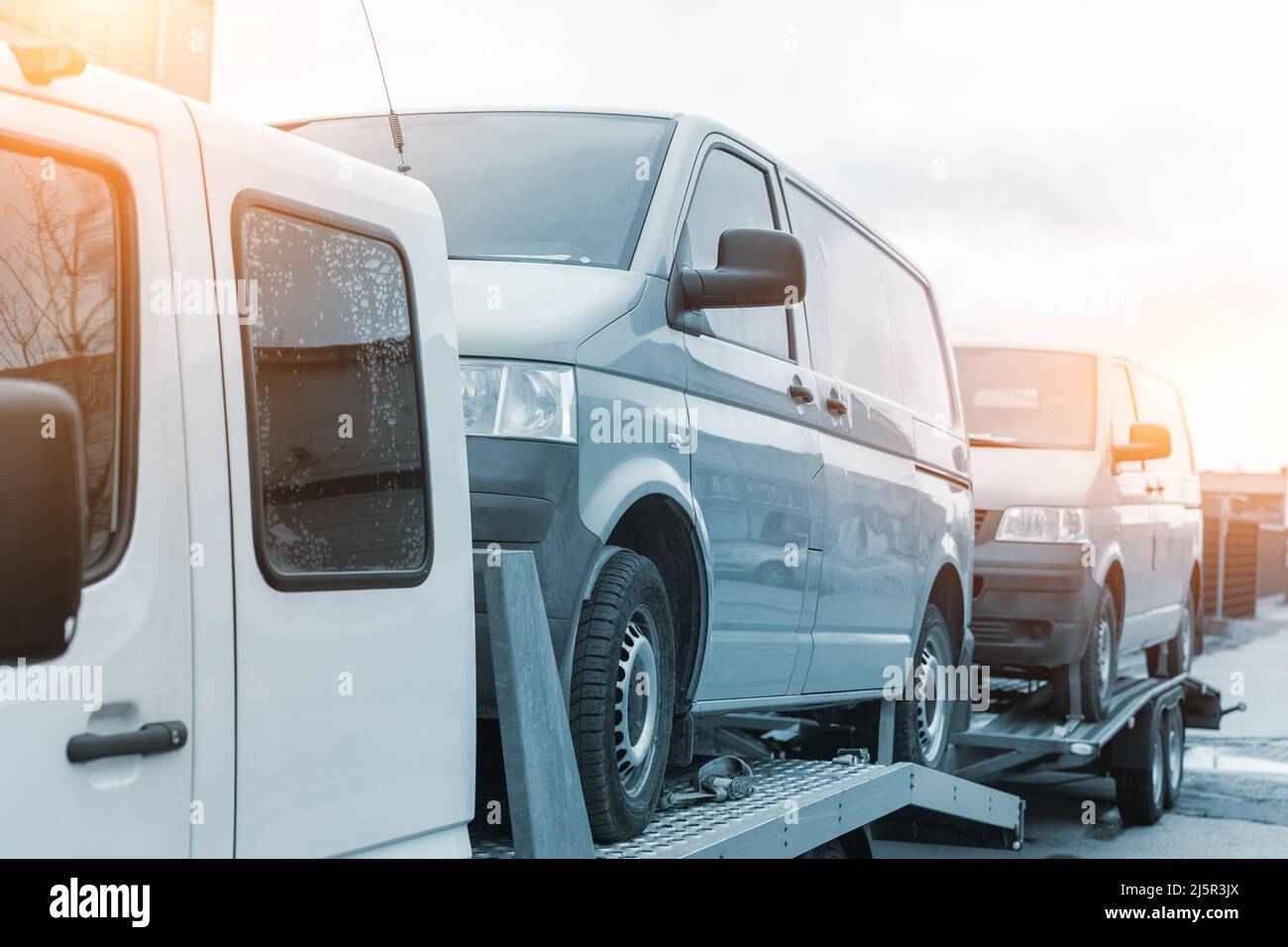 White small cargo truck car carrier loaded with two yellow van minibus ...