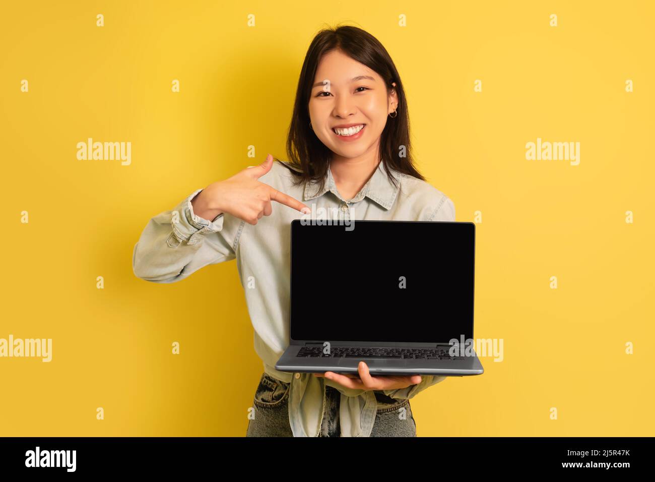 Check this website. Cheerful young Asian woman pointing at laptop with ...