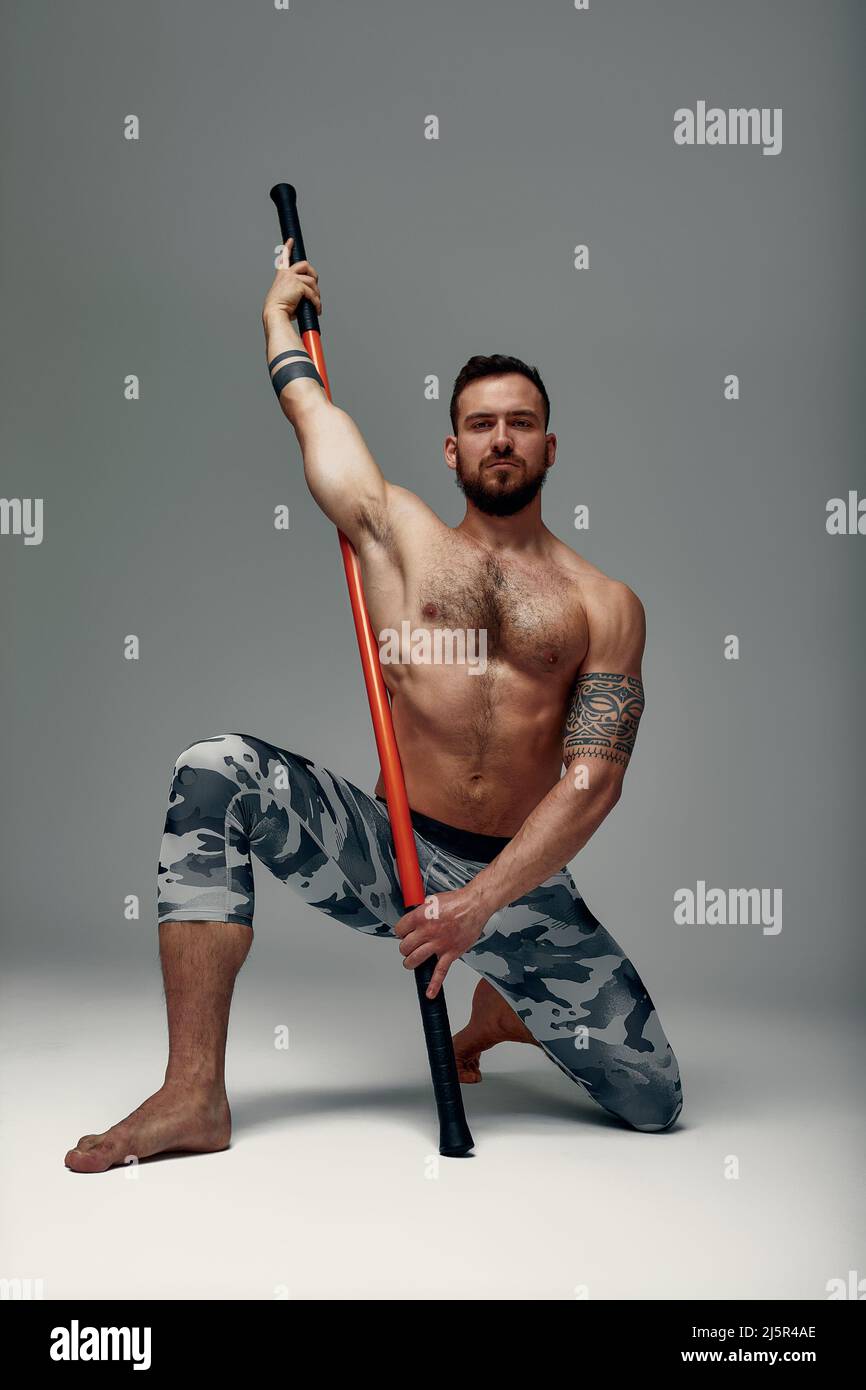 A ninja man holds on to a fighting stick and attacks close-up on gray ...