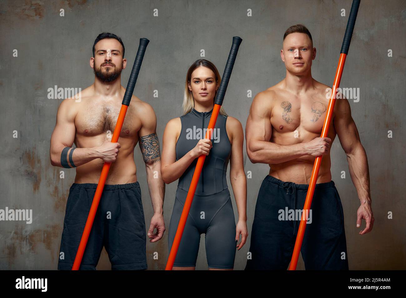 Two men and woman aikido fighters with wooden fight stick posing in ...