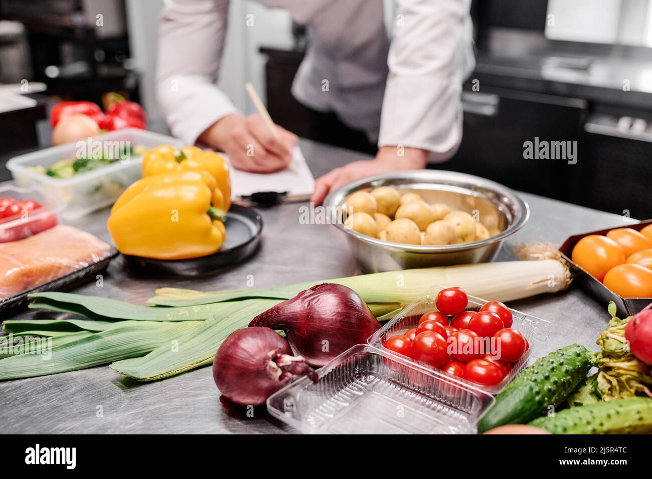 Close-up of fresh vegetables on table in commercial kitchen with chef ...