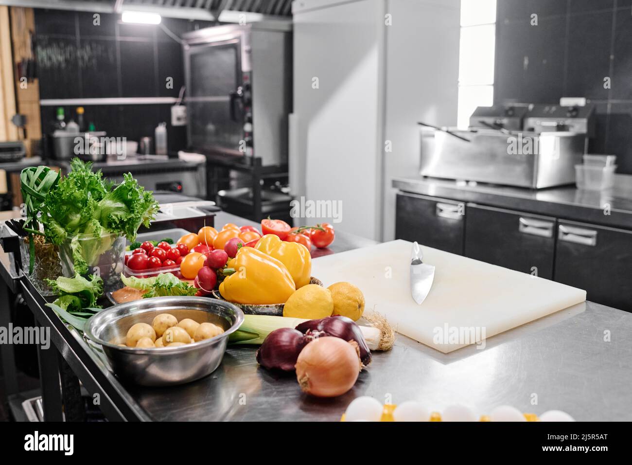 Image of workplace of chef with cutting board and fresh vegetables in ...