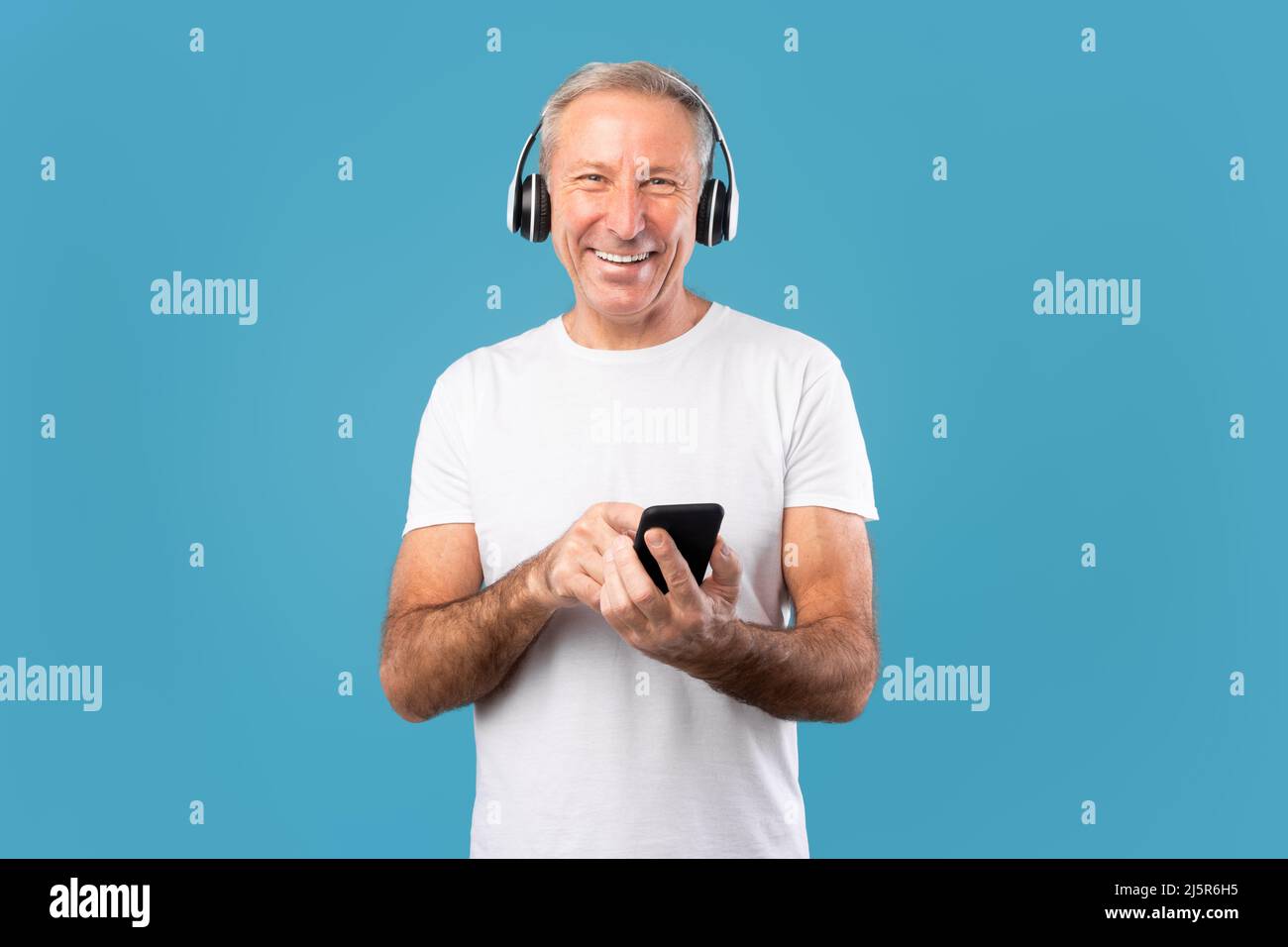 Mature man using his mobile phone wearing wireless headset Stock Photo ...