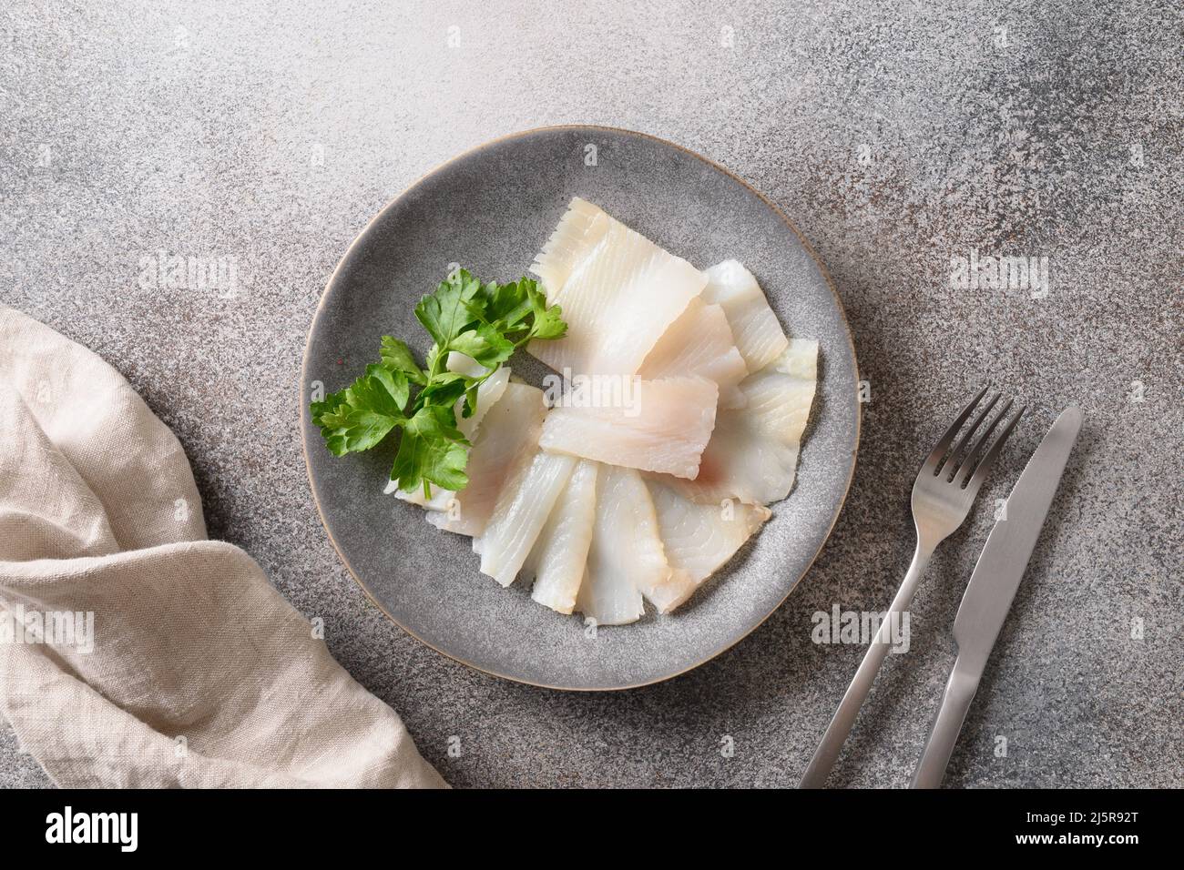 Delicious smoked halibut slices served with parsley on gray background ...
