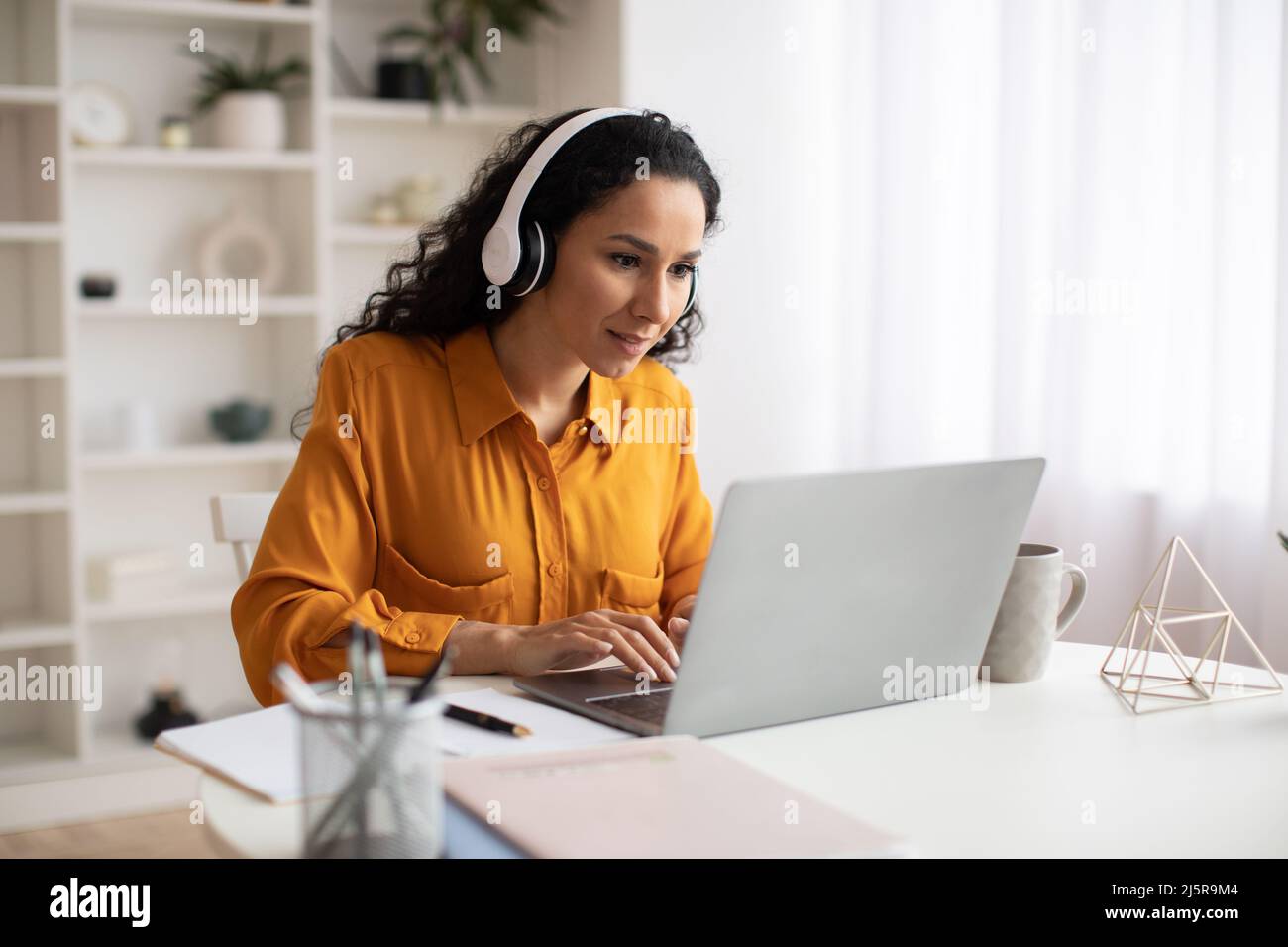Female Freelancer Using Laptop Wearing Headphones Working Online In ...