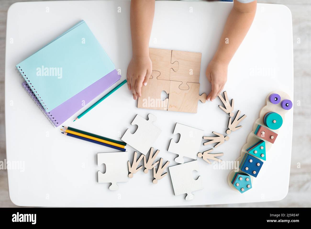 Top view of child holding wooden puzzle pieces, little hands connecting ...