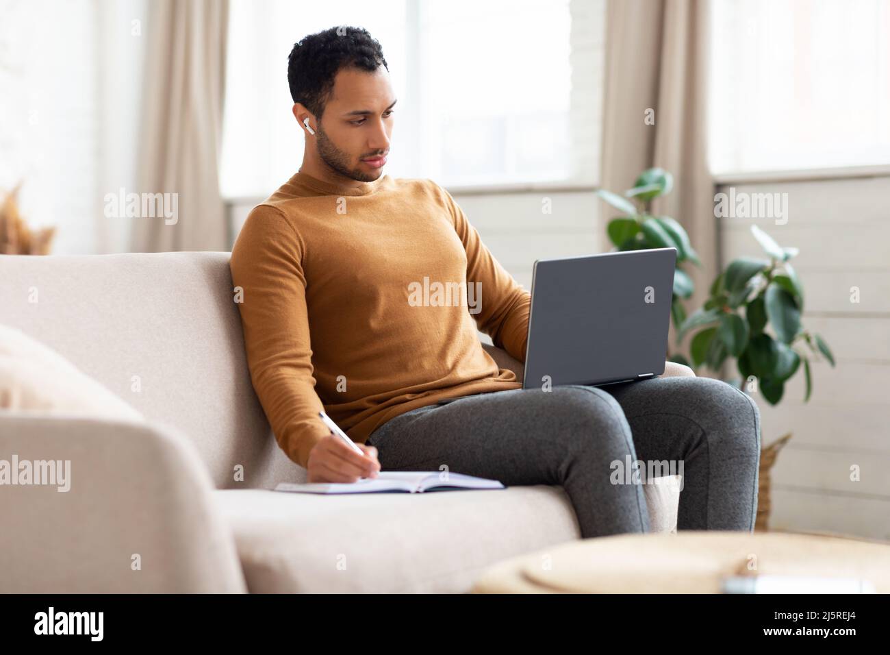 Portrait of focused Arab man using laptop taking notes Stock Photo - Alamy