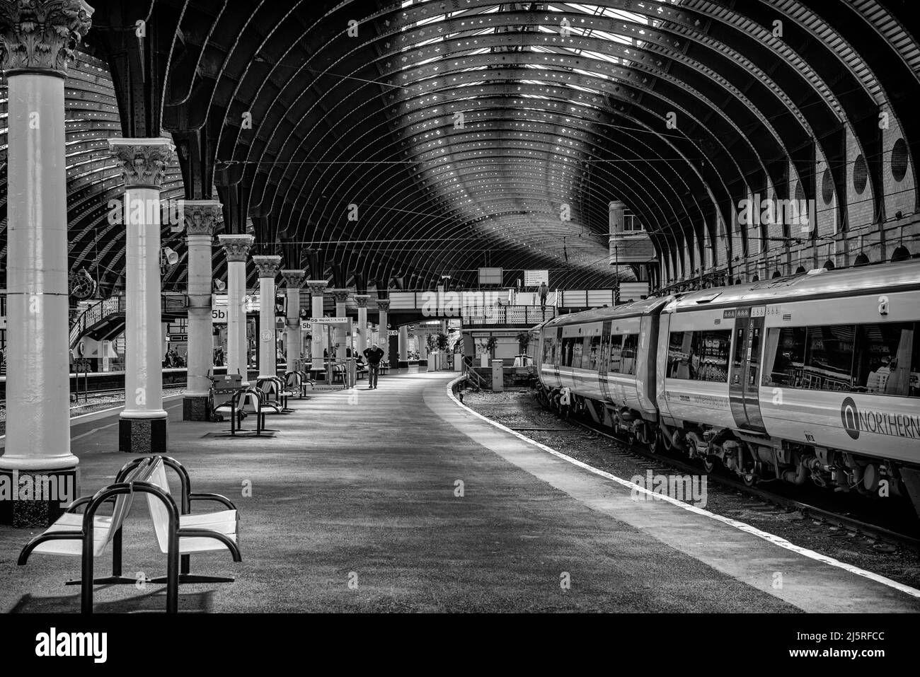 A historic railway station platform with an iron canopy curving ...