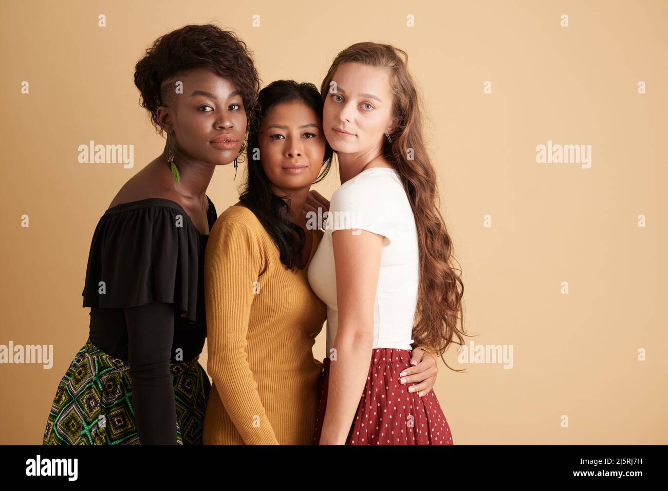 Group of unsmiling young female friends standing next to each other ...