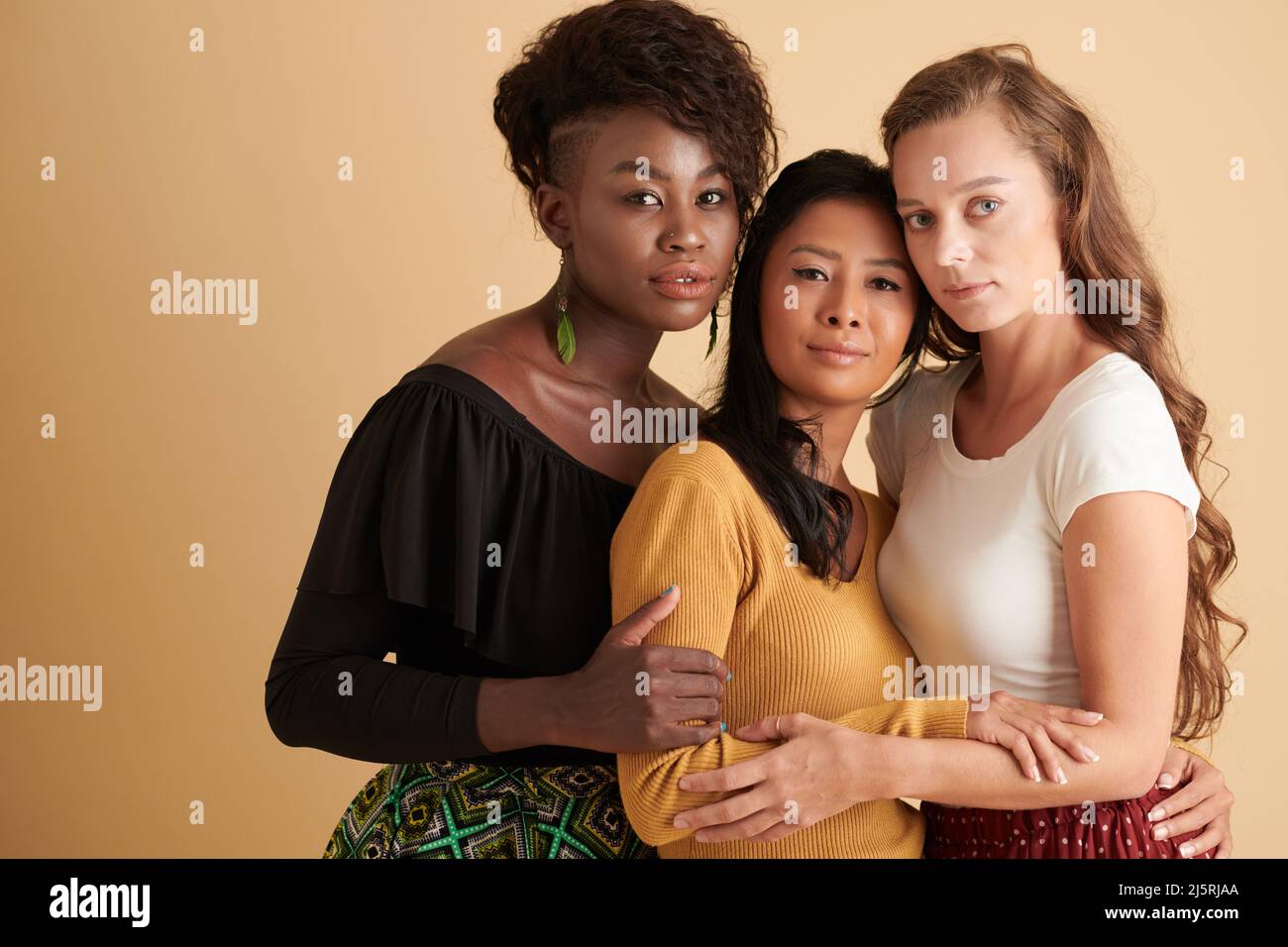 Portrait of three young women standing next to each other and looking ...