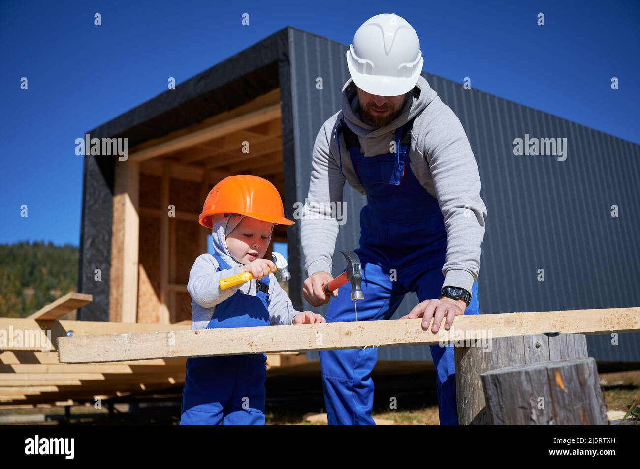 Father with toddler son building wooden frame house. Male builders ...