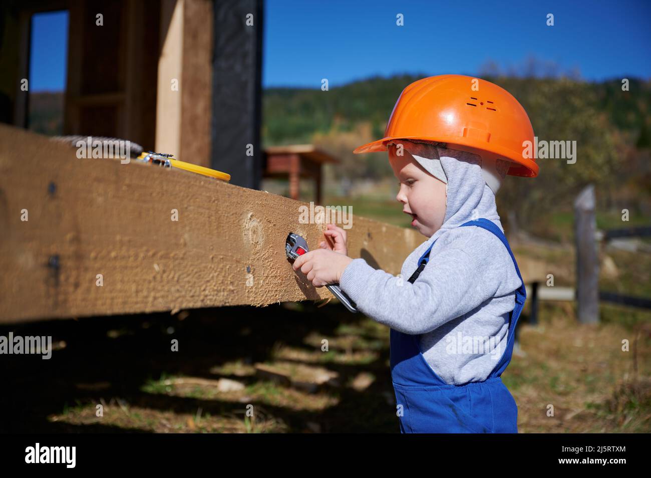 Boy toddler playing as builder on construction site. Child carpenter in ...